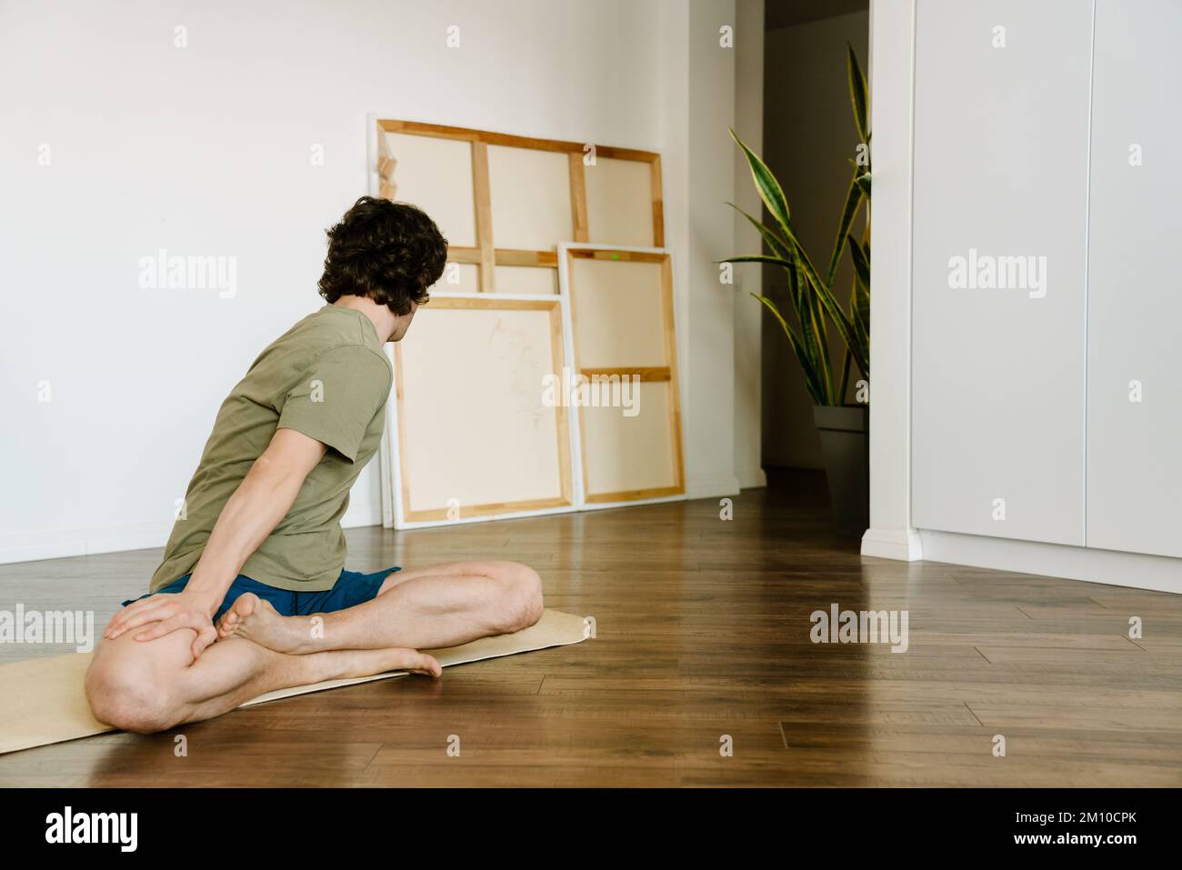 White man wearing shorts doing exercise during yoga practice at home ...