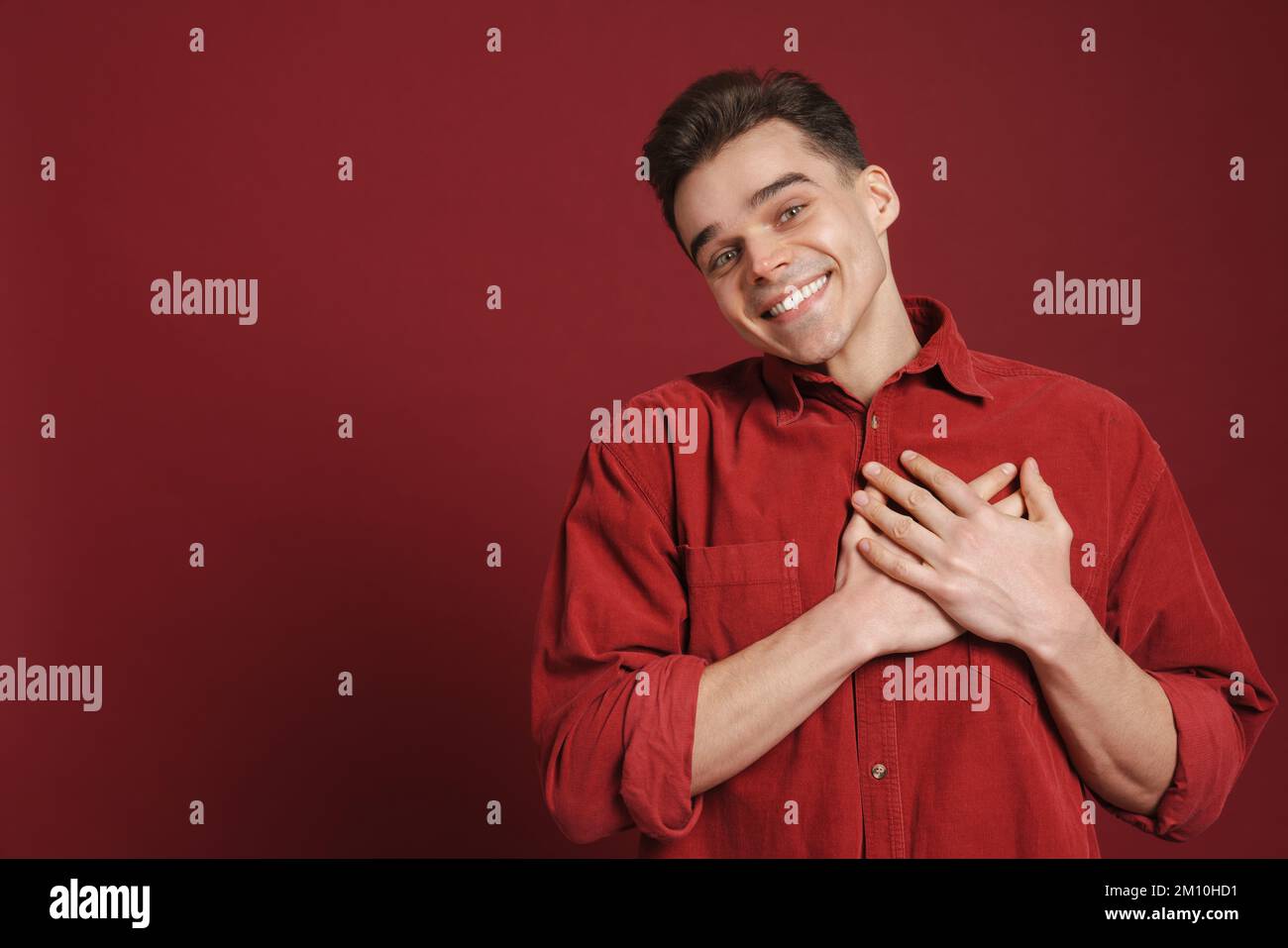 Young white man smiling and holding hands on his chest isolated over ...