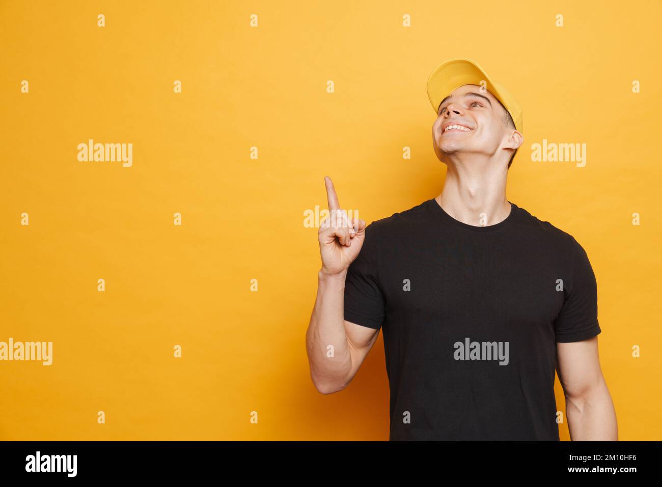 Young white man wearing cap smiling and pointing fingers upward ...