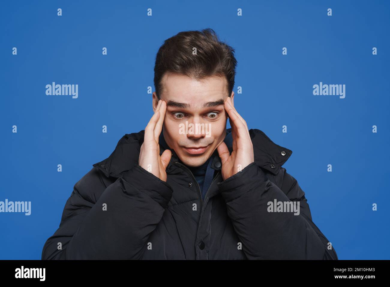 Shocked white man rubbing his temples and looking downward isolated ...