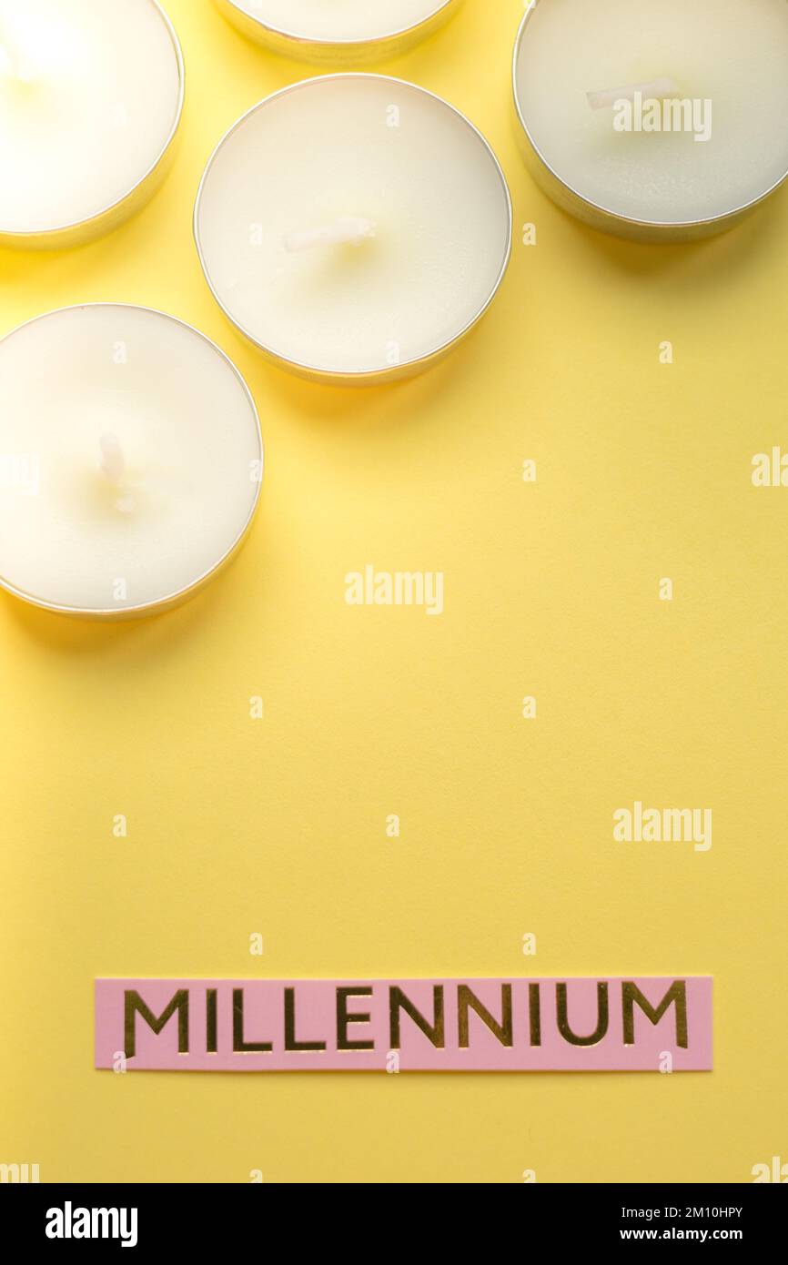 Pink paper with text millennium and white candles on yellow table Stock ...