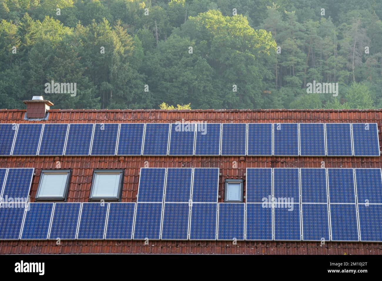 An aerial view of solar panels on the brown roof of a building with ...