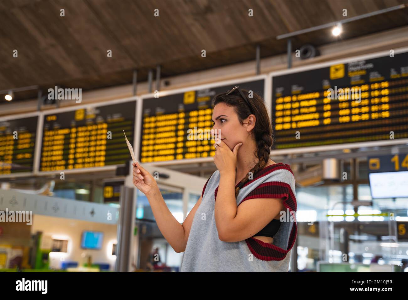 brunette girl with braid at the airport looking at the flight board ...