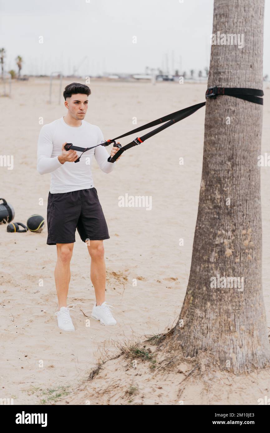 A young fit Spanish athletic male doing shoulder pull exercises with a ...