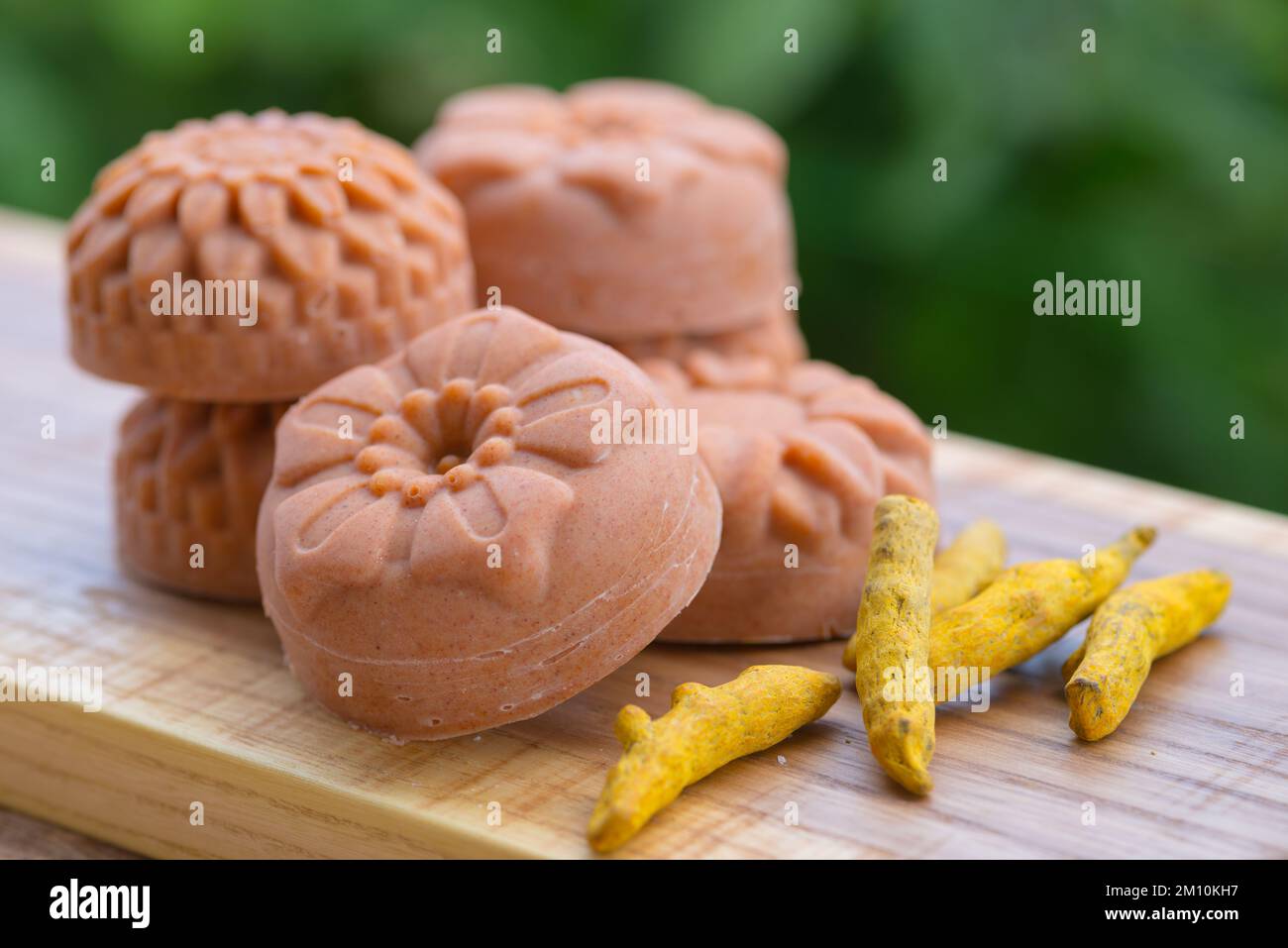 Round orange soap in the form of flowers with turmeric on a green ...