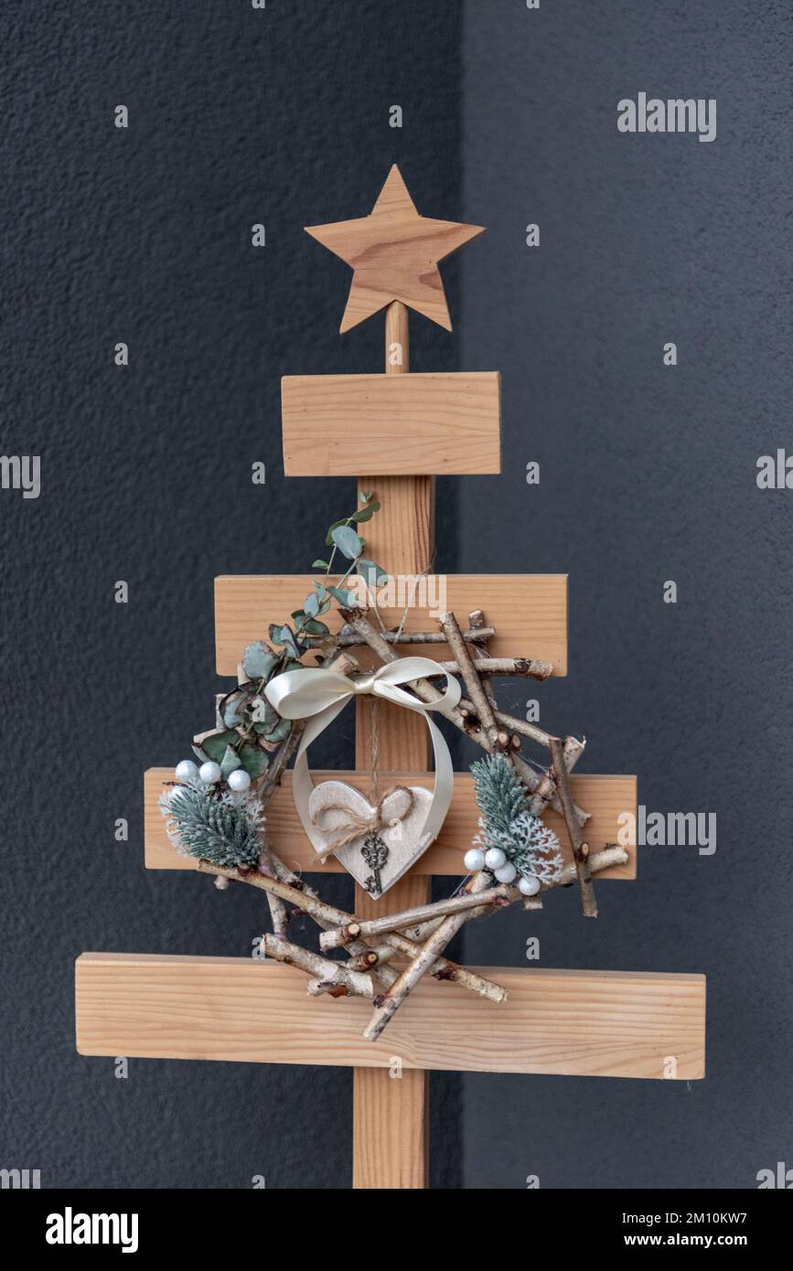 A wooden Christmas tree with decorations on a gray wall background ...