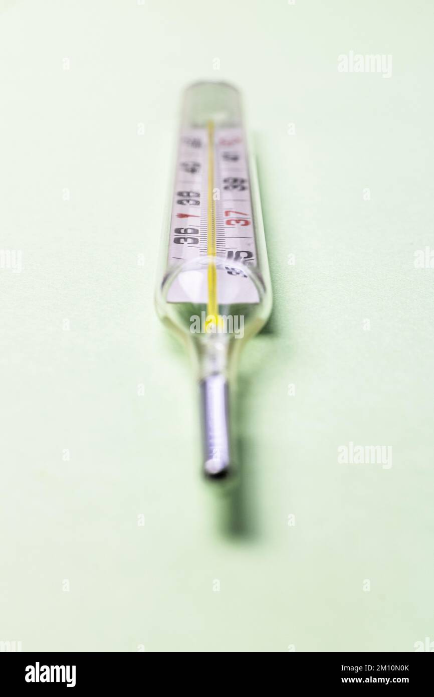 Mercury thermometer on table with green background Stock Photo - Alamy
