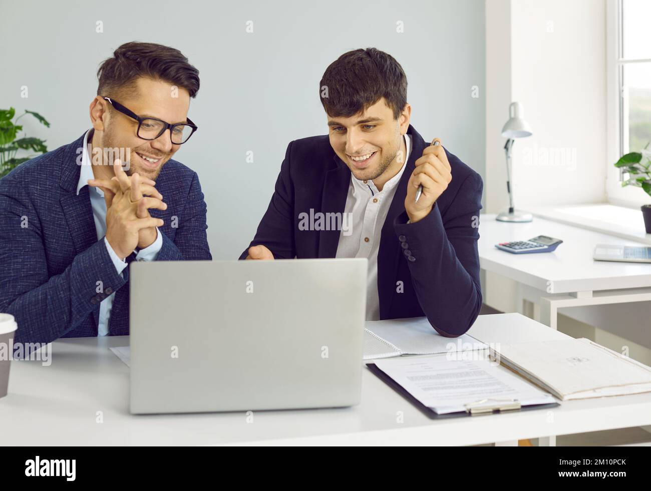 Two happy successful business people using laptop computer while ...