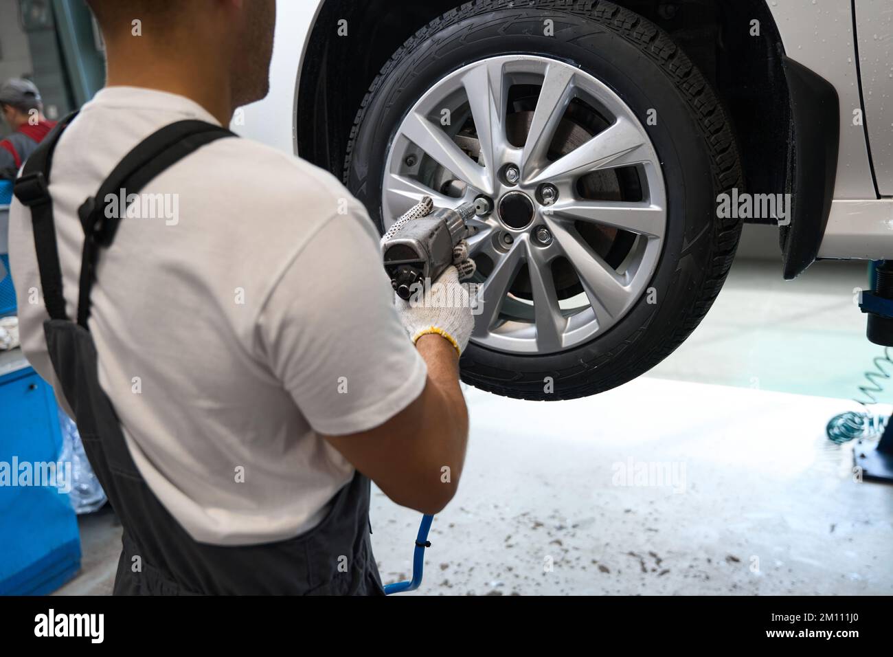Man changing car wheel in tire fitting Stock Photo - Alamy