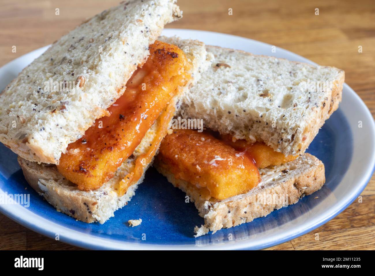 Fish finger sandwich with tomato ketchup on a blue plate Stock Photo ...