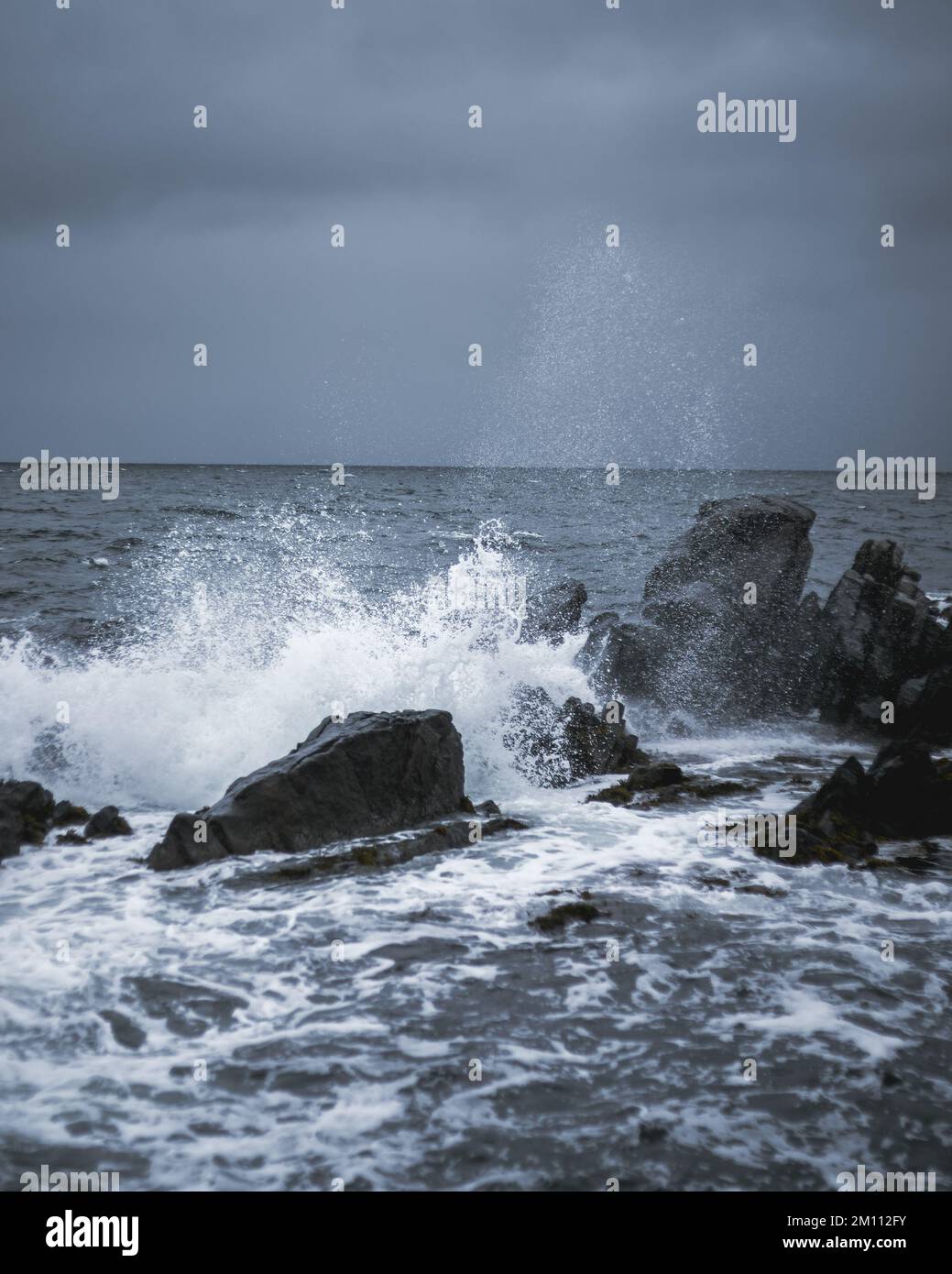 The waves of the ocean crashing into the rocks and splashing, in a ...