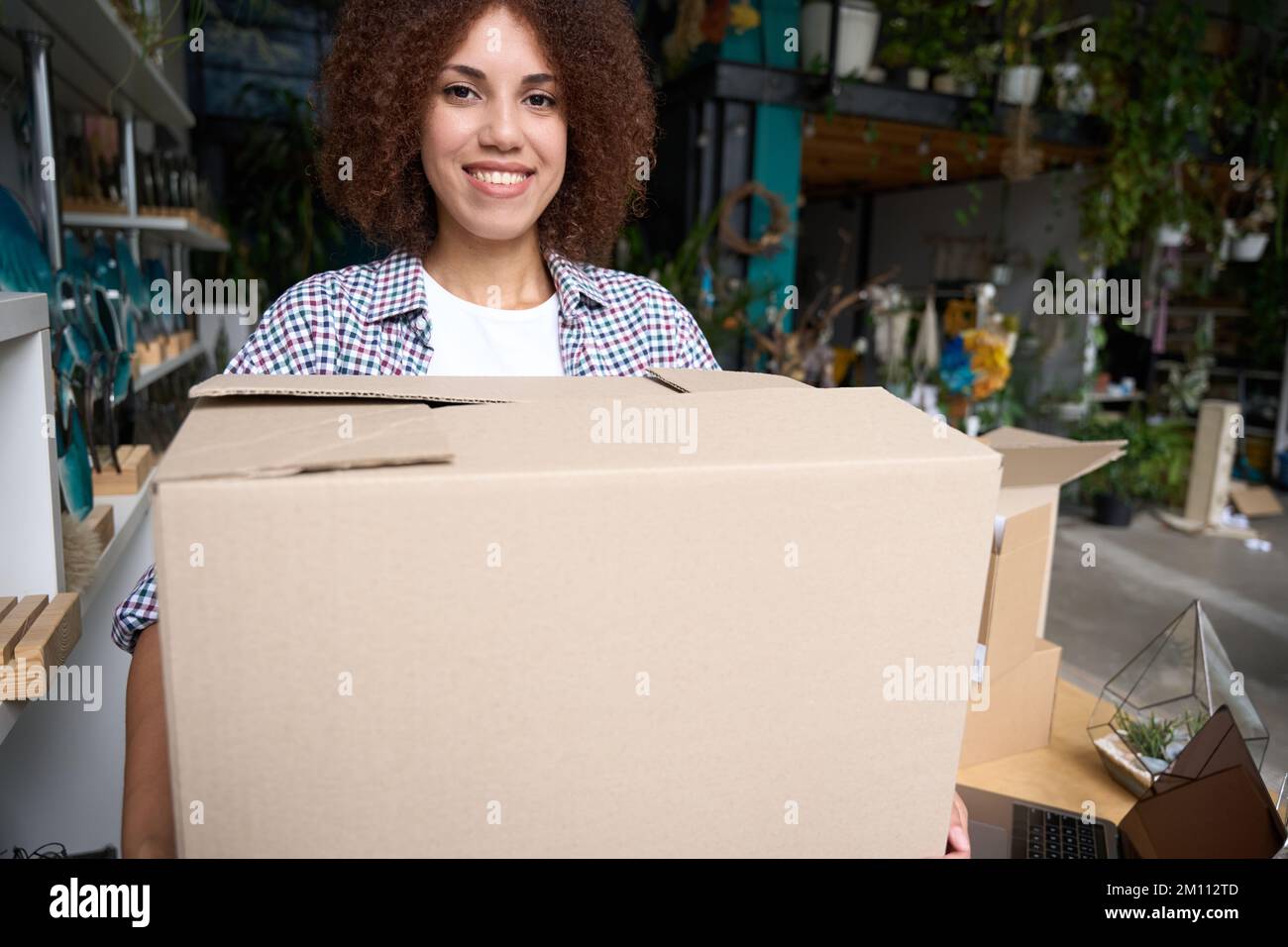 Merry woman carrying carton box in flower shop Stock Photo - Alamy