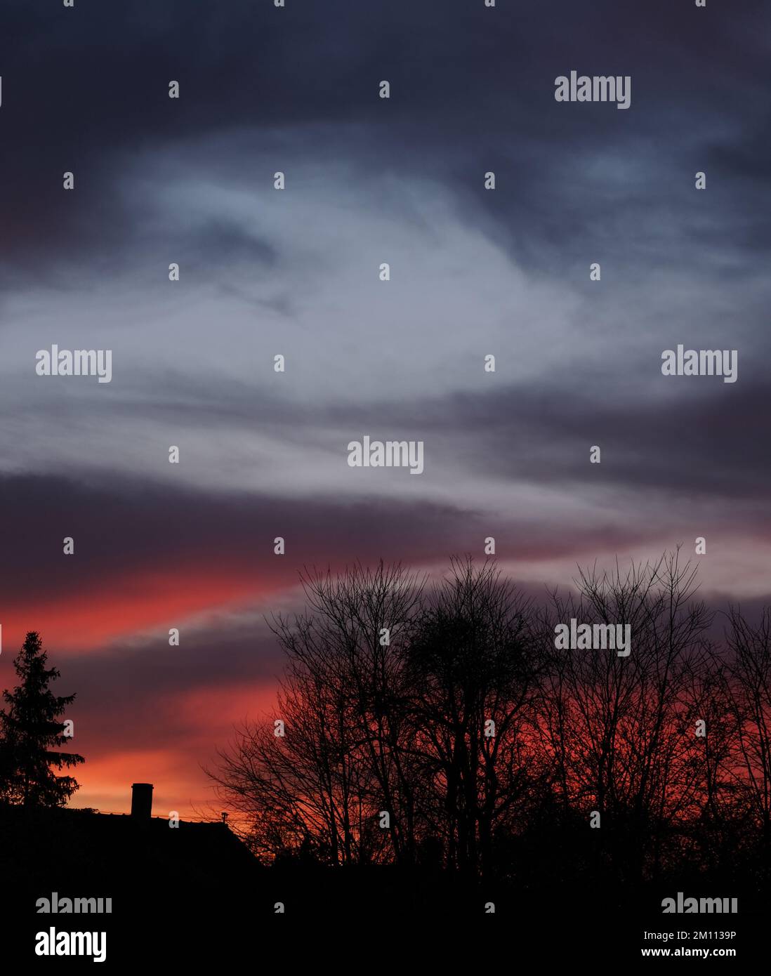 Burning clouds - red blue navy blue sky, house and trees in the ...
