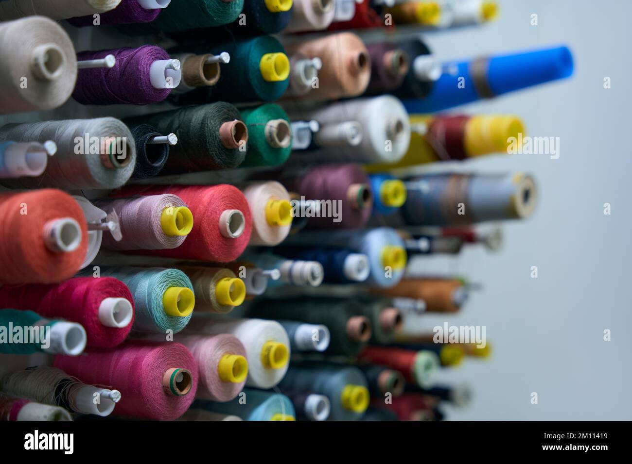 Multi-colored spools of thread on special holders Stock Photo - Alamy
