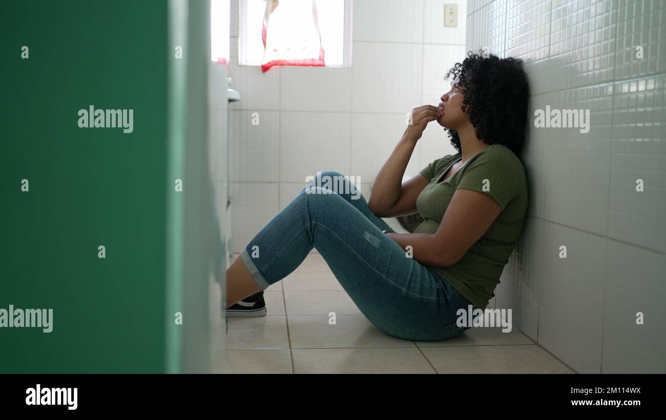 Sad worried woman sitting on floor at home during difficult times ...
