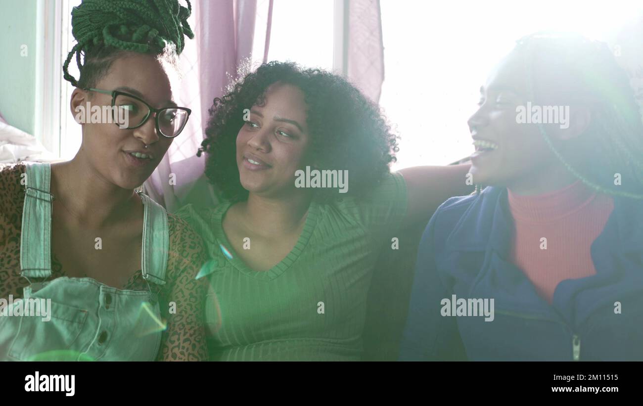 Three happy Brazilian women laughing and smiling at camera sitting at ...
