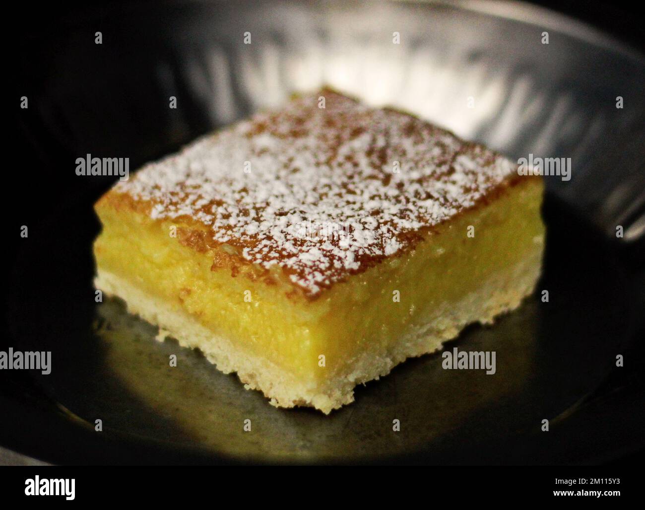 A closeup shot of a piece of a lemon cake with a powder on it on the ...