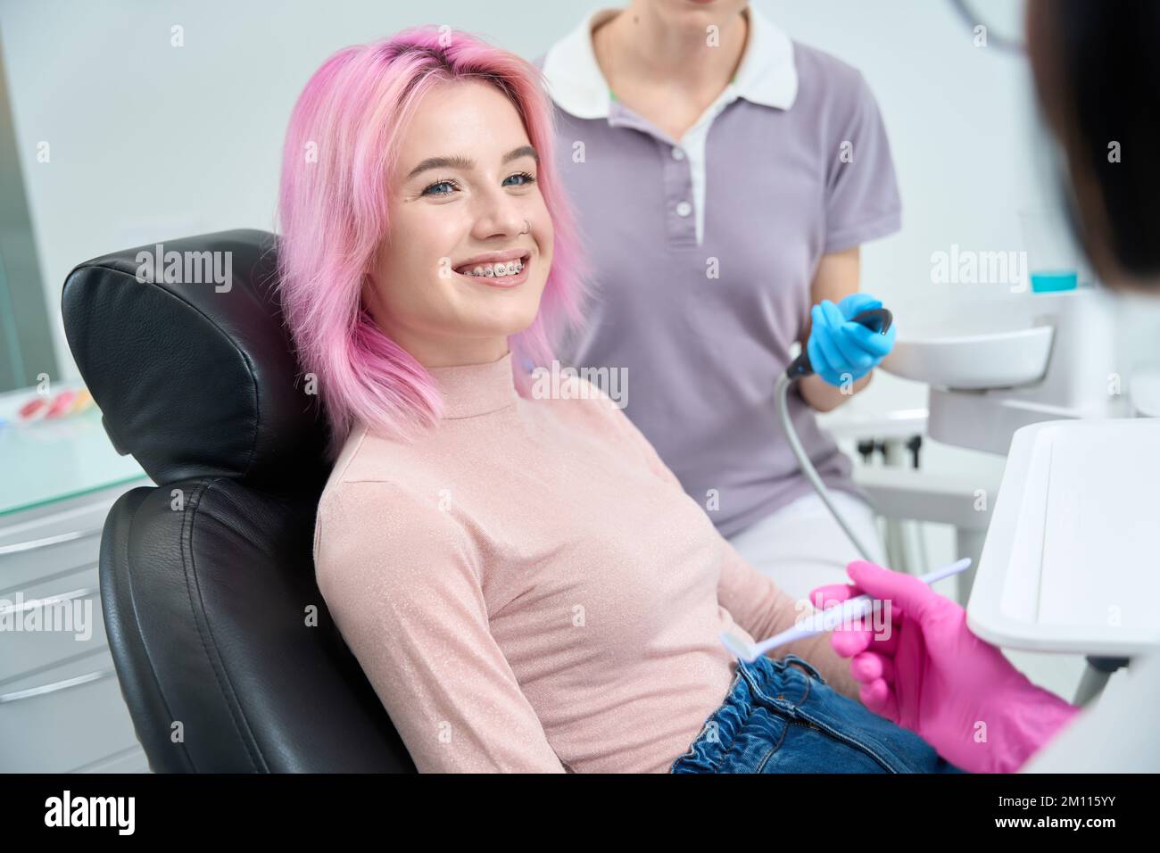 Pink-haired smiling woman with braces at the reception at dentist Stock ...
