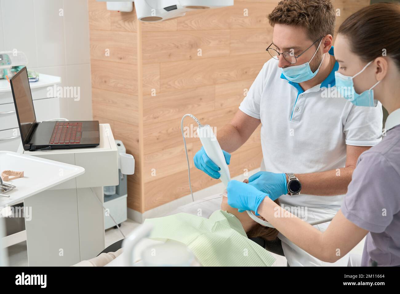 Dental staff examining client teeth with digital intraoral scanner ...