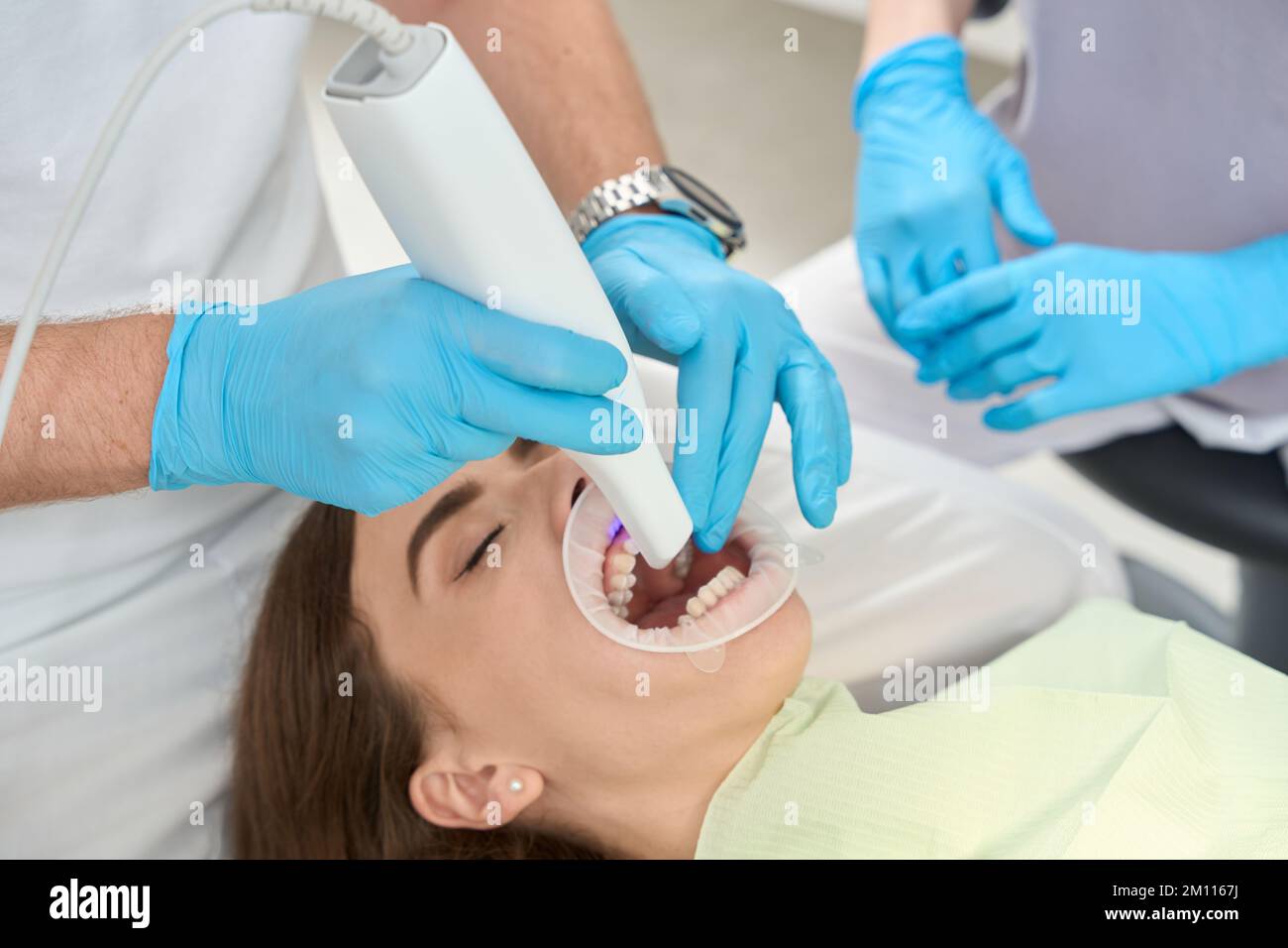 Experienced doctor performing examination of woman mouth using modern ...