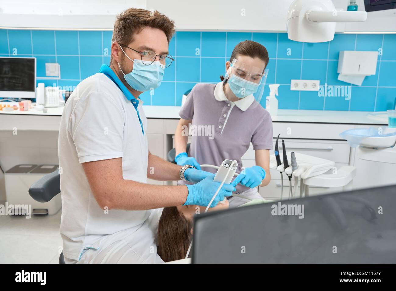 Serious focused stomatologist examining client teeth using modern ...