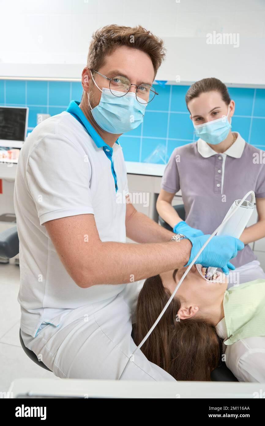 Stomatologist scanning oral cavity of young woman with diagnostic ...