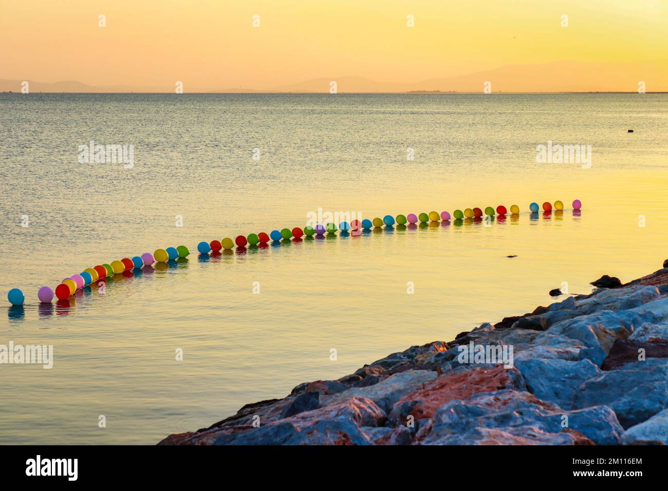 An aerial shot of colorful balloons in a row near a beach of a sea ...