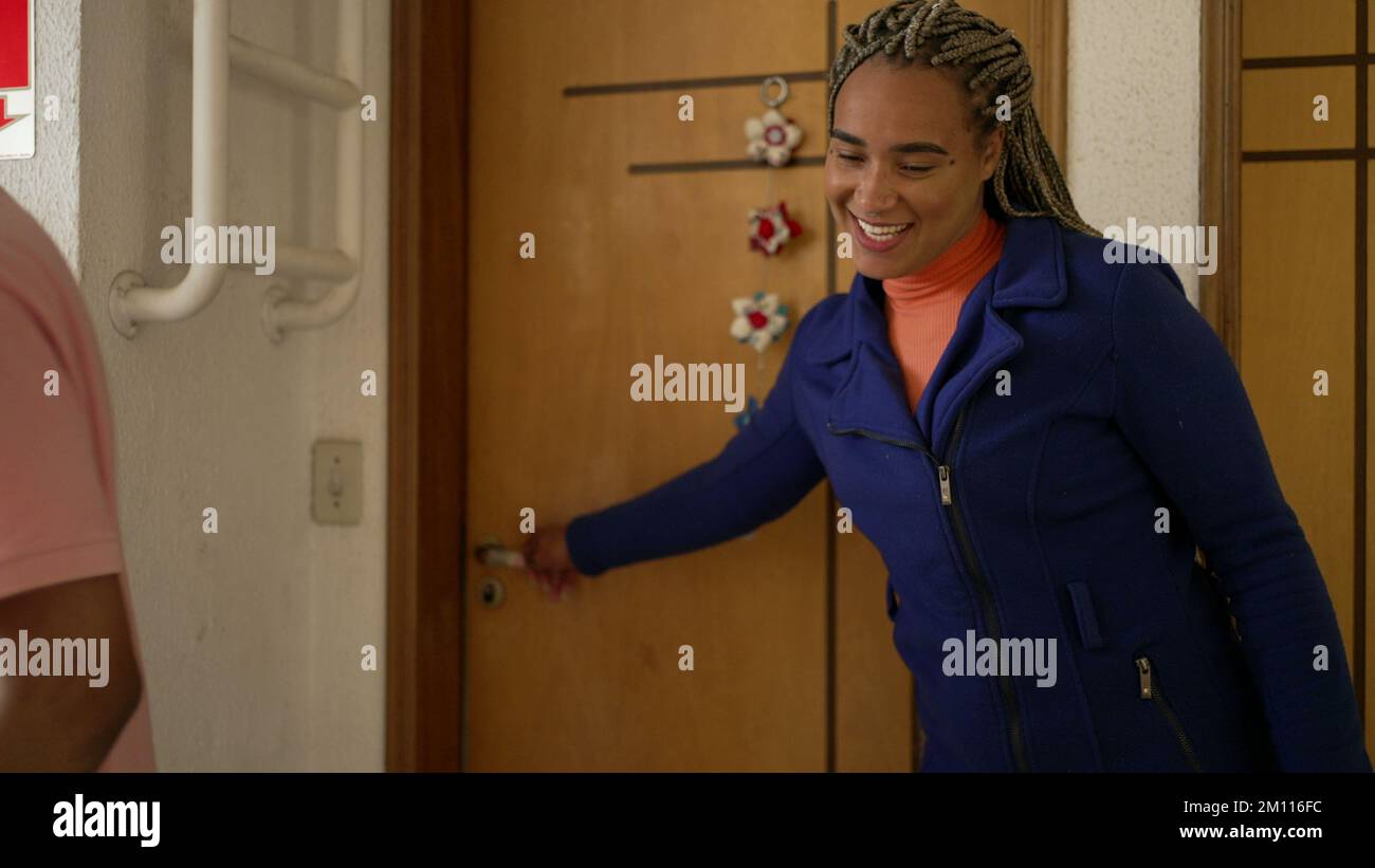 A young black woman closing entrance door. African American adult girl ...