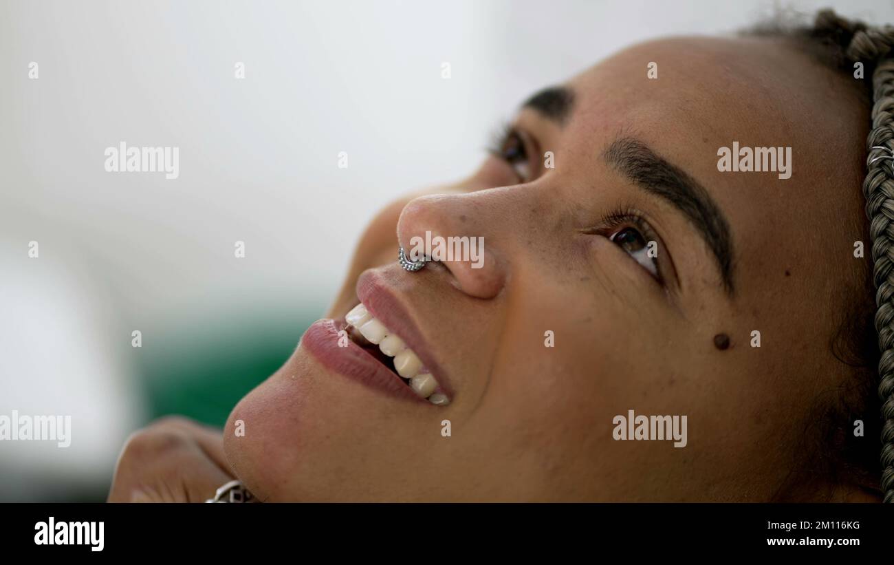 Closeup young hispanic woman face looking at sky smiling. Hopeful ...