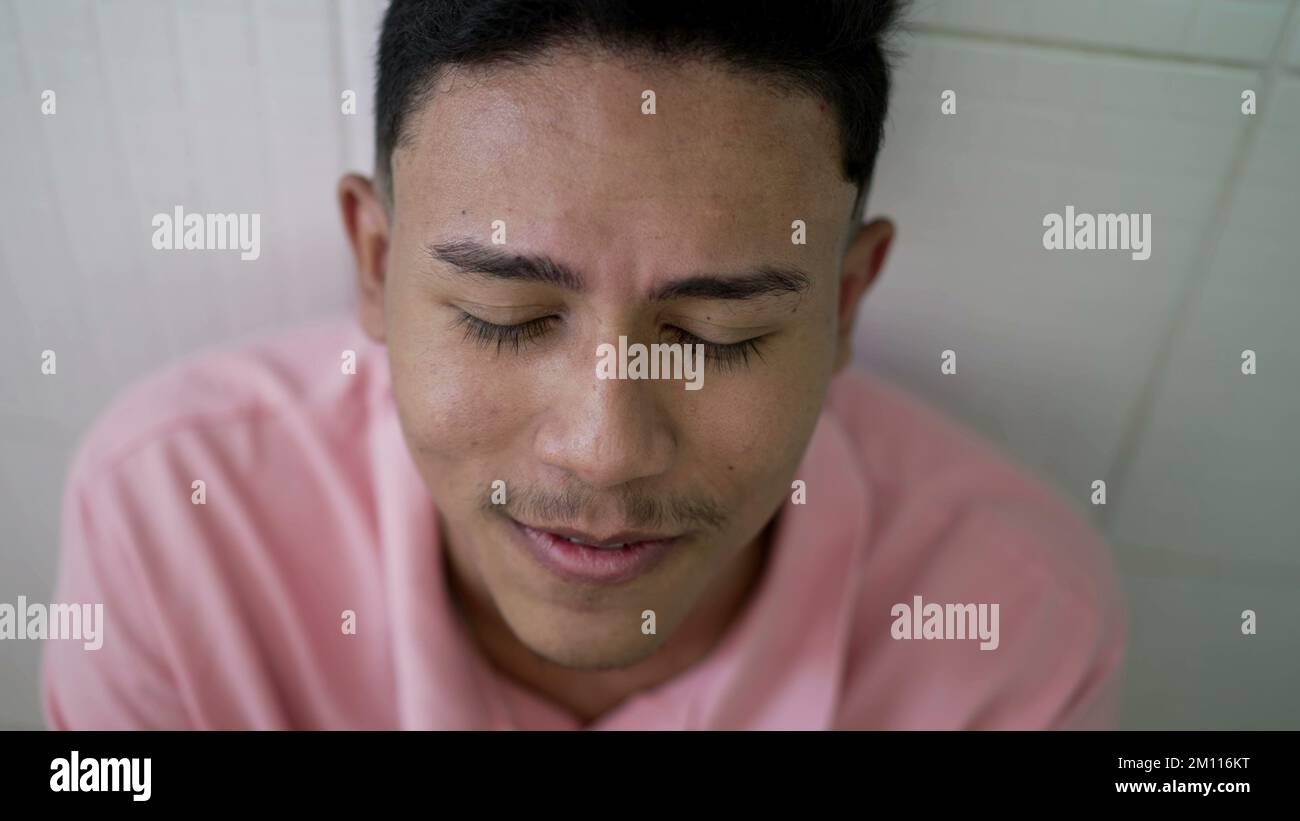 Evangelical young Brazilian man raising hands up while head bows down ...