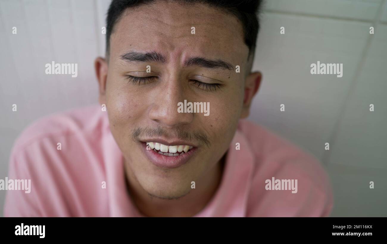 Evangelical young Brazilian man raising hands up while head bows down ...