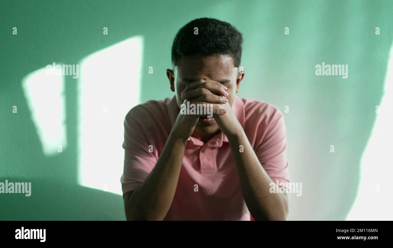 Faithful young hispanic man praying to God hands folded in worship ...