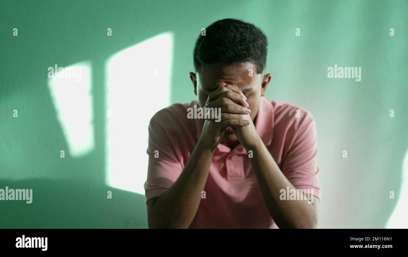 Faithful young hispanic man praying to God hands folded in worship ...
