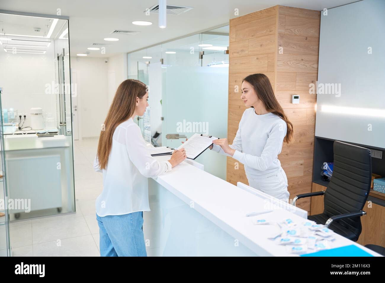 Client affixing signature to document at reception desk Stock Photo - Alamy