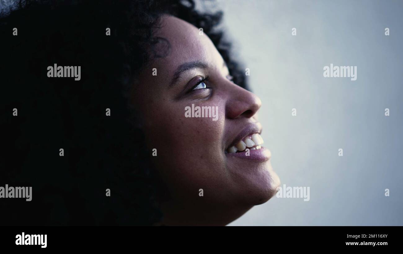 One hopeful meditative young black woman with eyes closed in ...