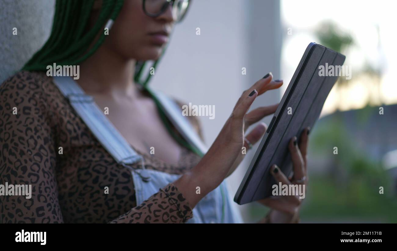 One young black woman using tablet outdoors. African American adult ...