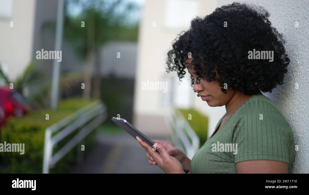 One young black woman using tablet outdoors. African American adult ...
