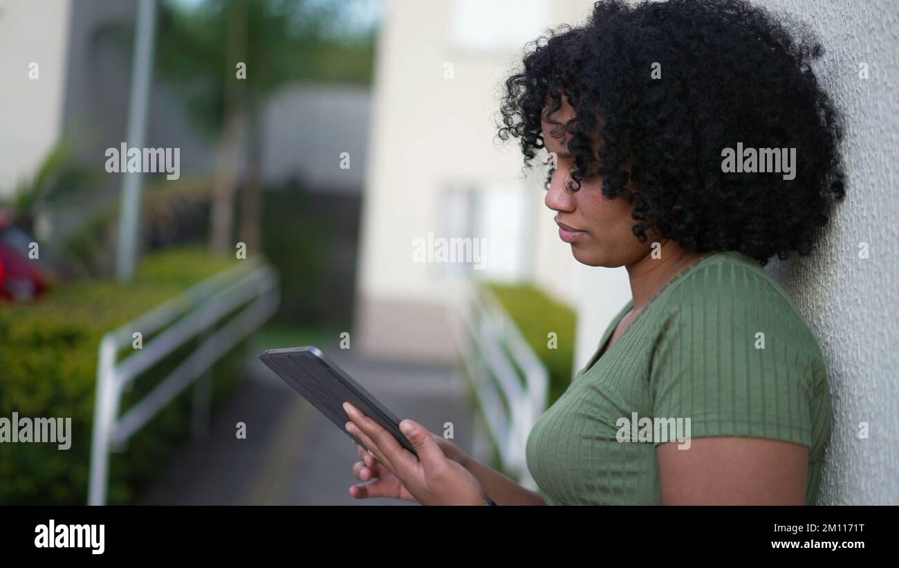 One young black woman using tablet outdoors. African American adult ...