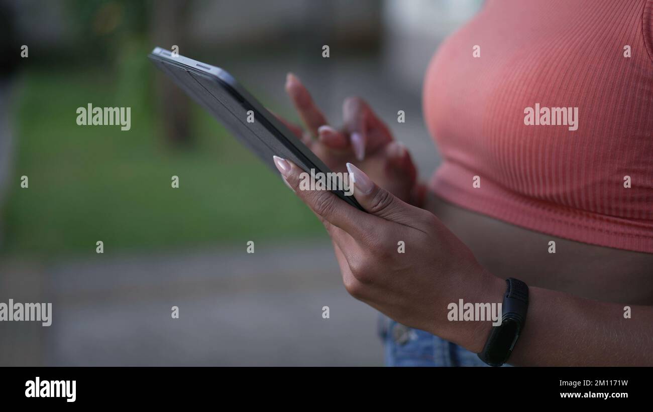 One young black woman using tablet outdoors. African American adult ...