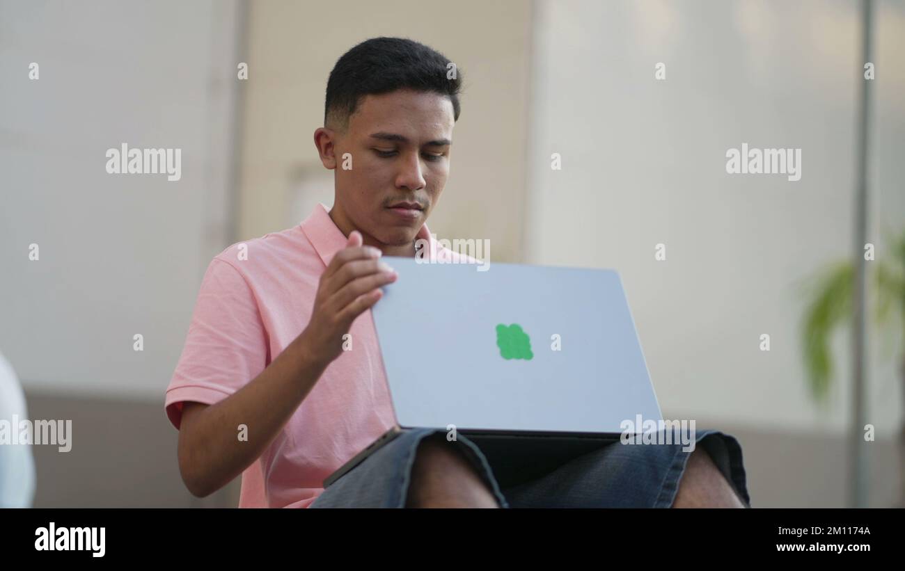 One young hispanic man shutting laptop off. Male person turning ...