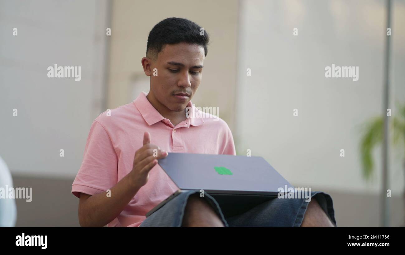 One young hispanic man shutting laptop off. Male person turning ...