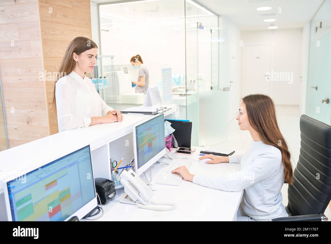 Waiting client and busy female secretary in clinic foyer Stock Photo ...
