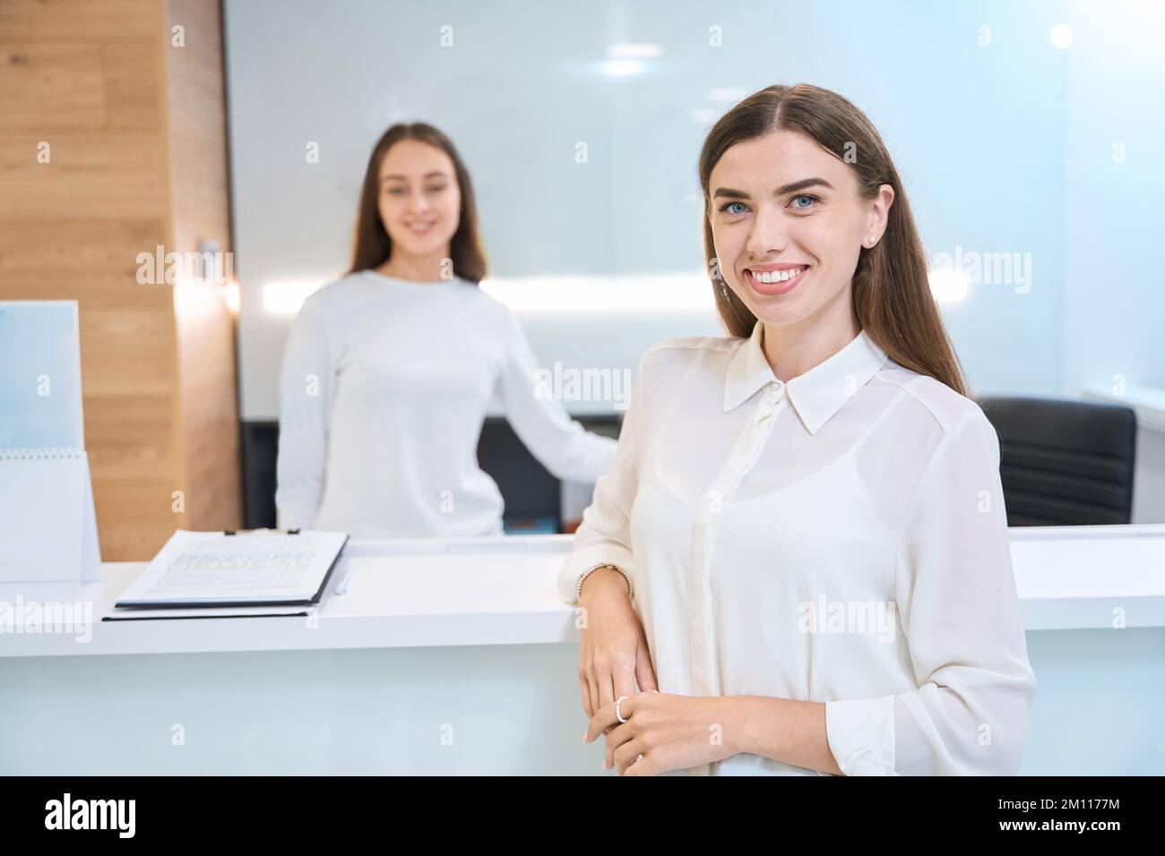 Joyous customer and secretary at reception desk Stock Photo - Alamy