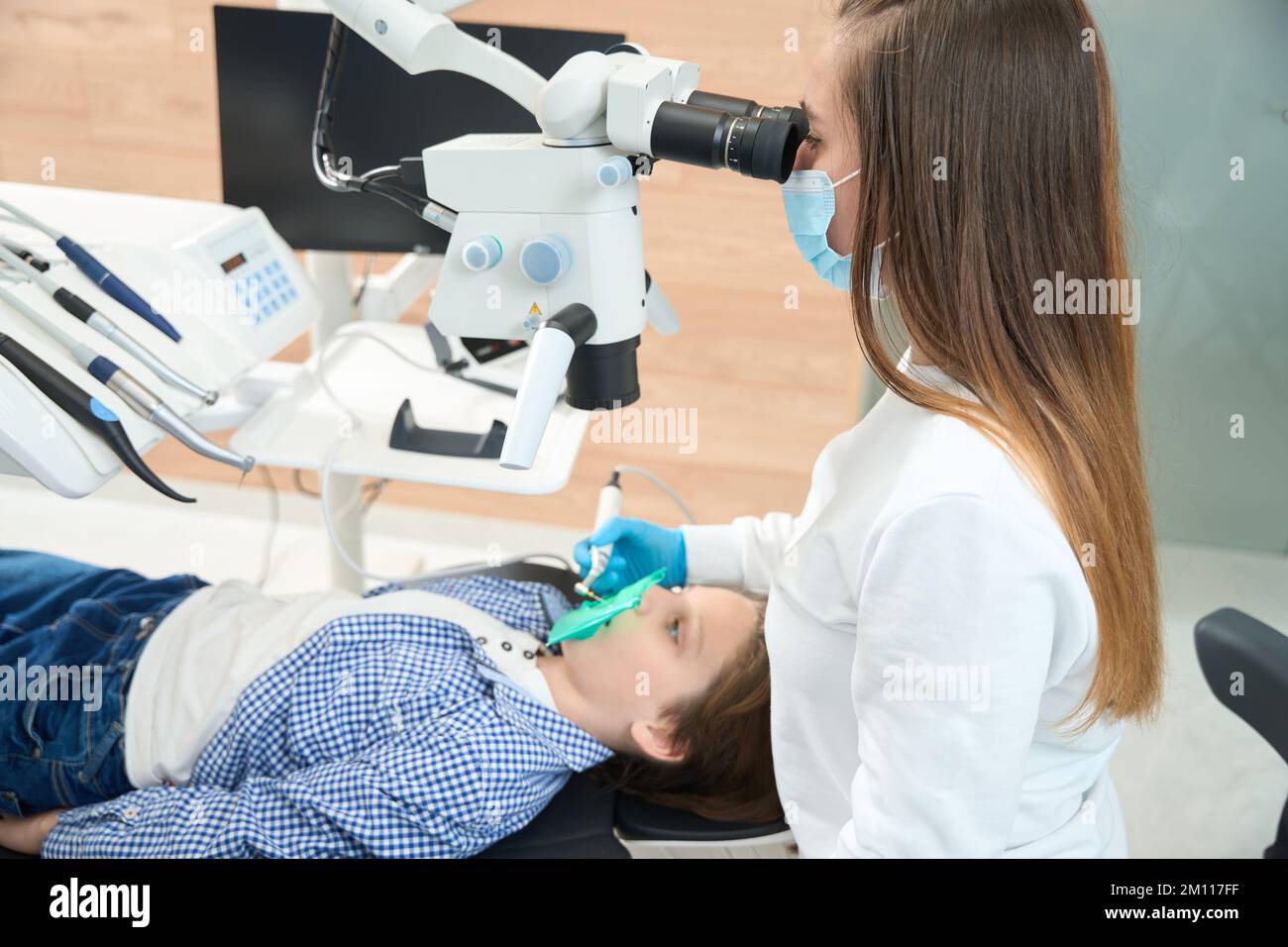 Woman dentist is treating a boy tooth under a microscope Stock Photo ...