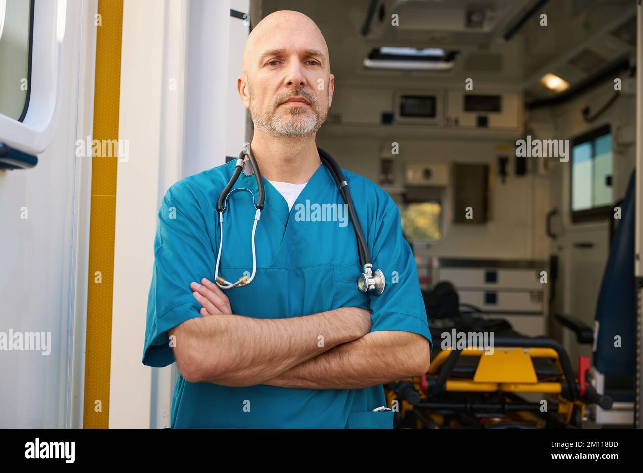 Medical officer with stethoscope around neck stands near an ambulance ...