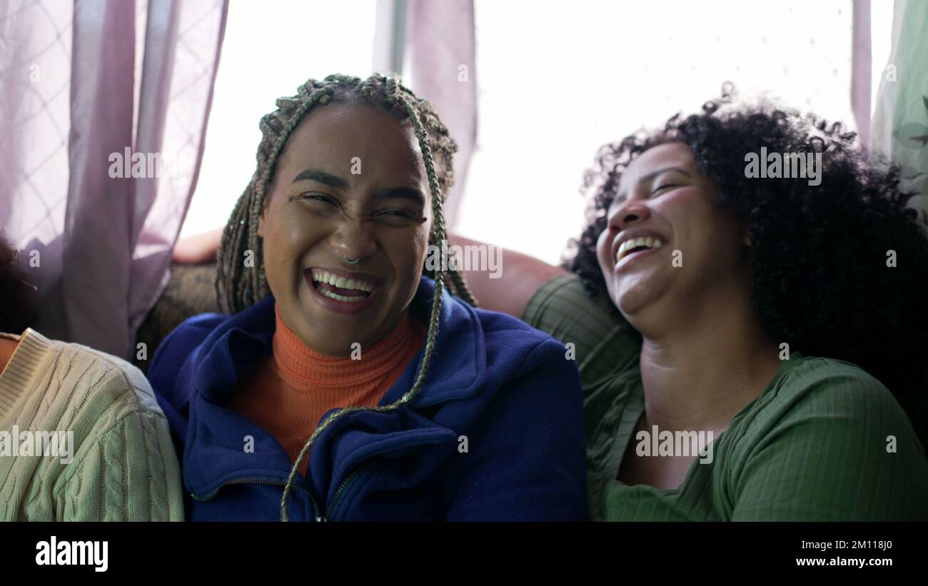 Happy Brazilian women seated at couch laughing together. Joyful South ...