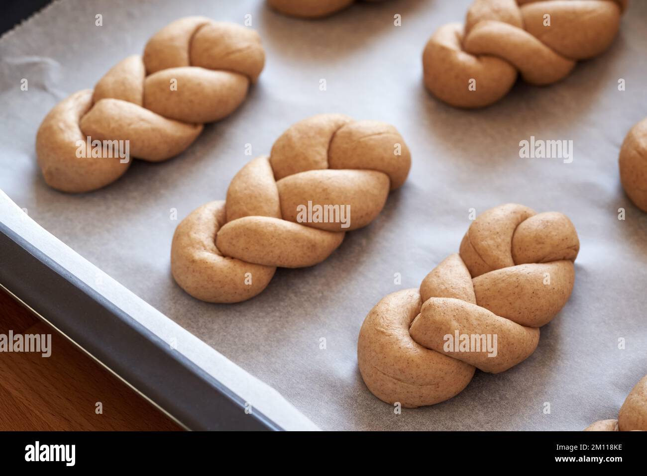 Raw braided bread buns made of whole grain spelt flour on a baking ...
