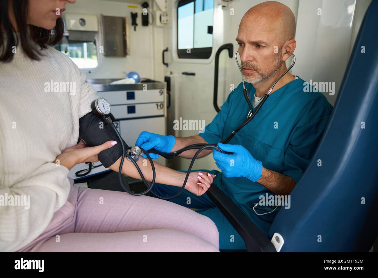 Doctor is measuring internal blood pressure of patient on ambulance ...