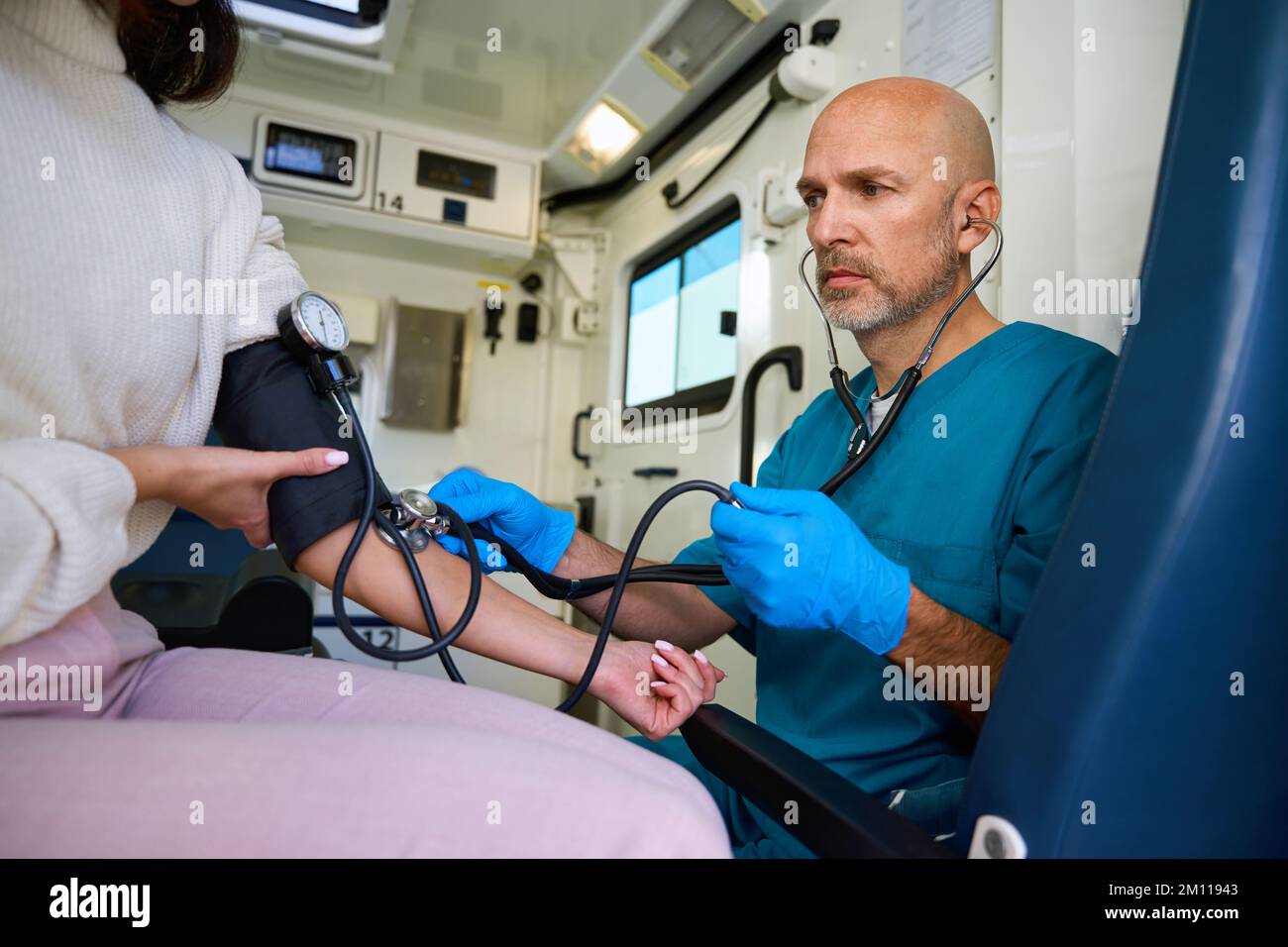 Man From Modern Medical Service Measures Blood Pressure In Patient man-from-modern-medical-service-measures-blood-pressure-in-patient
