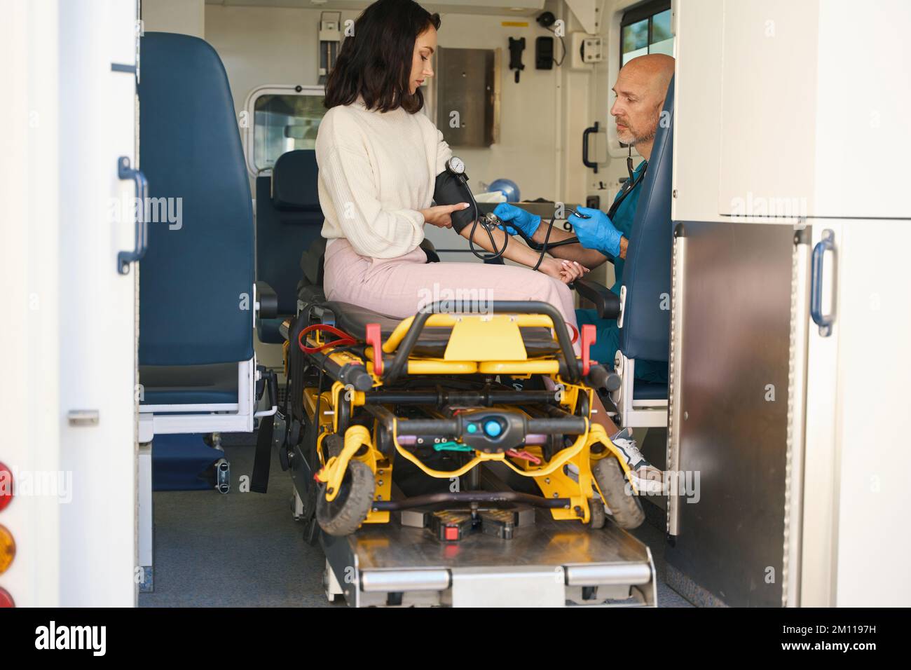 Woman sits in an ambulance with blood pressure monitor on arm Stock ...